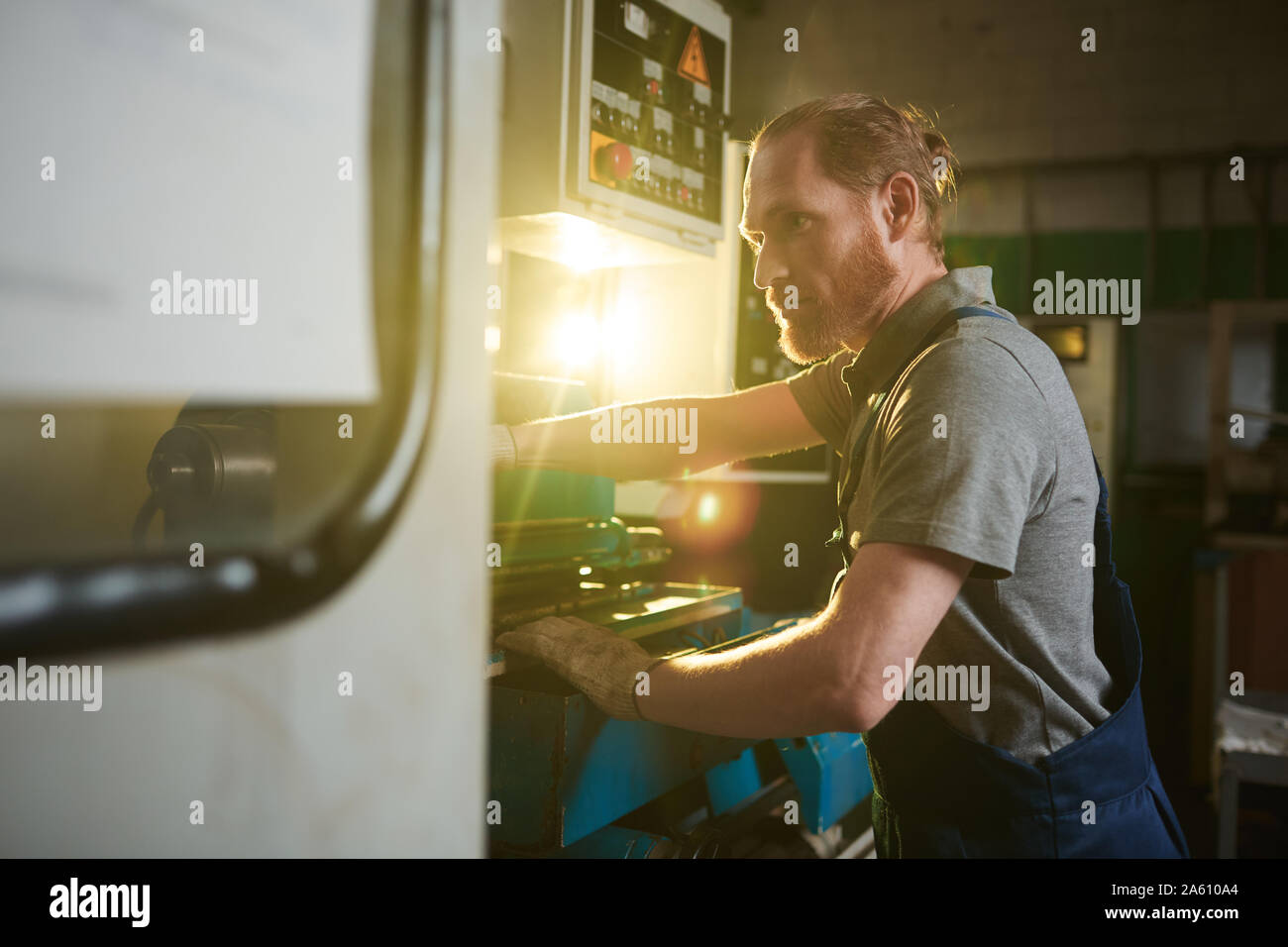 Manual worker in overalls concentrating on his work he standing and ...