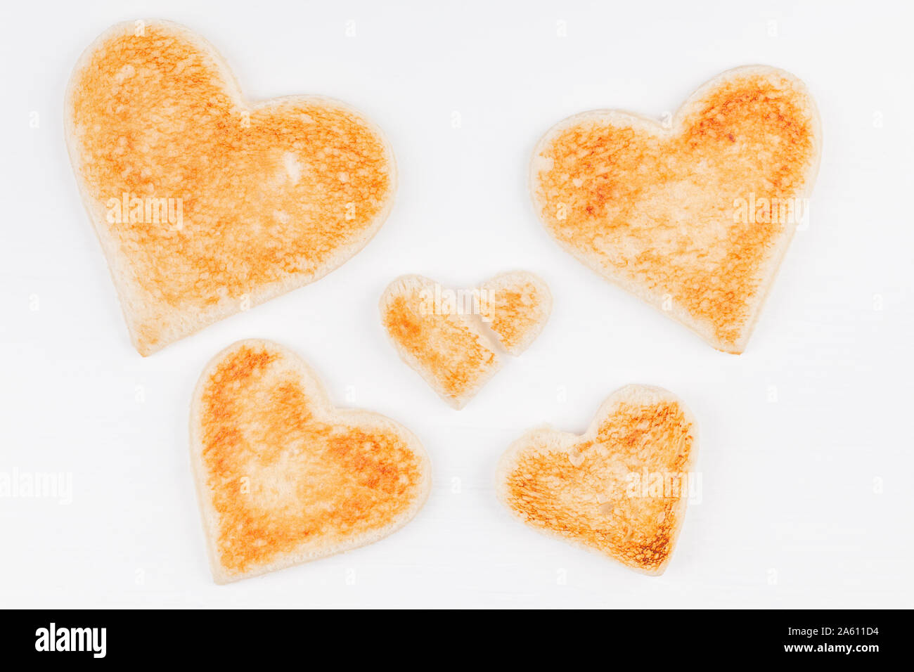 Group of toasted bread hearts with one broken heart together on white ...