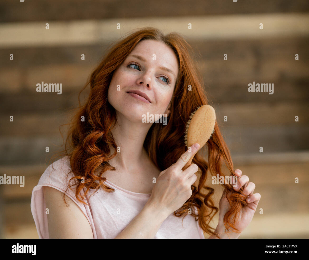 Portrait of smiling redheaded woman brushing her hair Stock Photo - Alamy