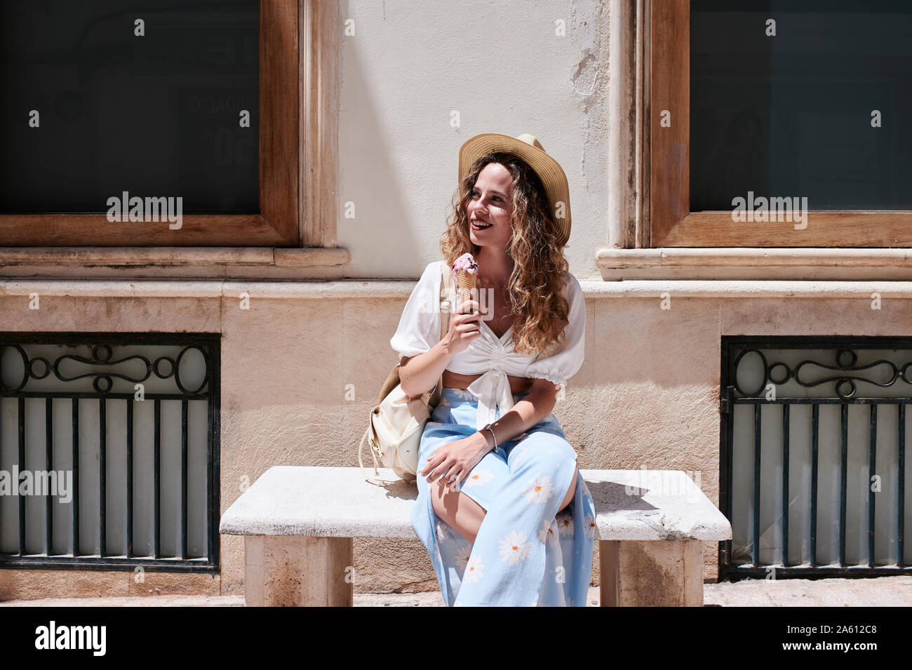 Young woman sitting on stone bench eating ice cream Stock Photo - Alamy