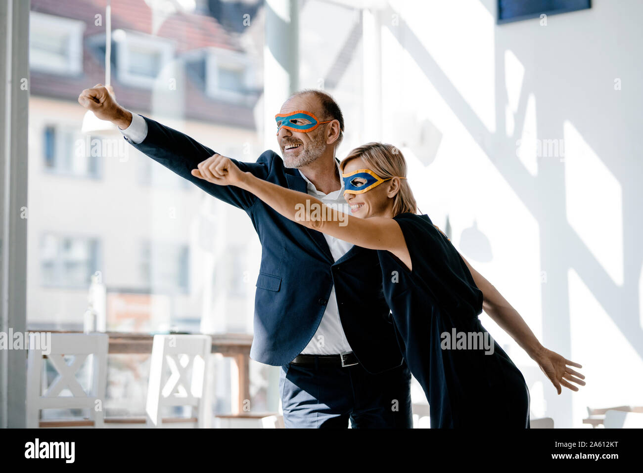 Businessman and woman wearing super hero masks, pretending to fly Stock ...