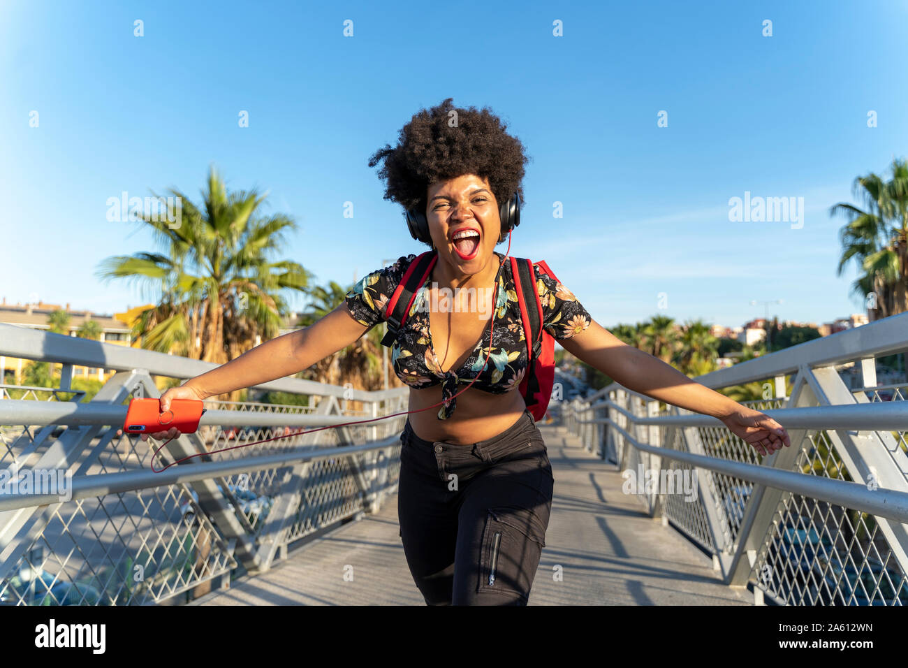 Female Afro-American with headphones and smartphone listening music ...