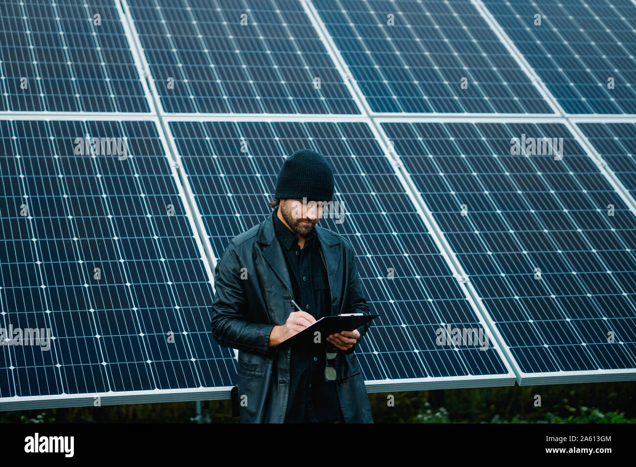 Man make notes into clipboard beside of solar panels Stock Photo - Alamy