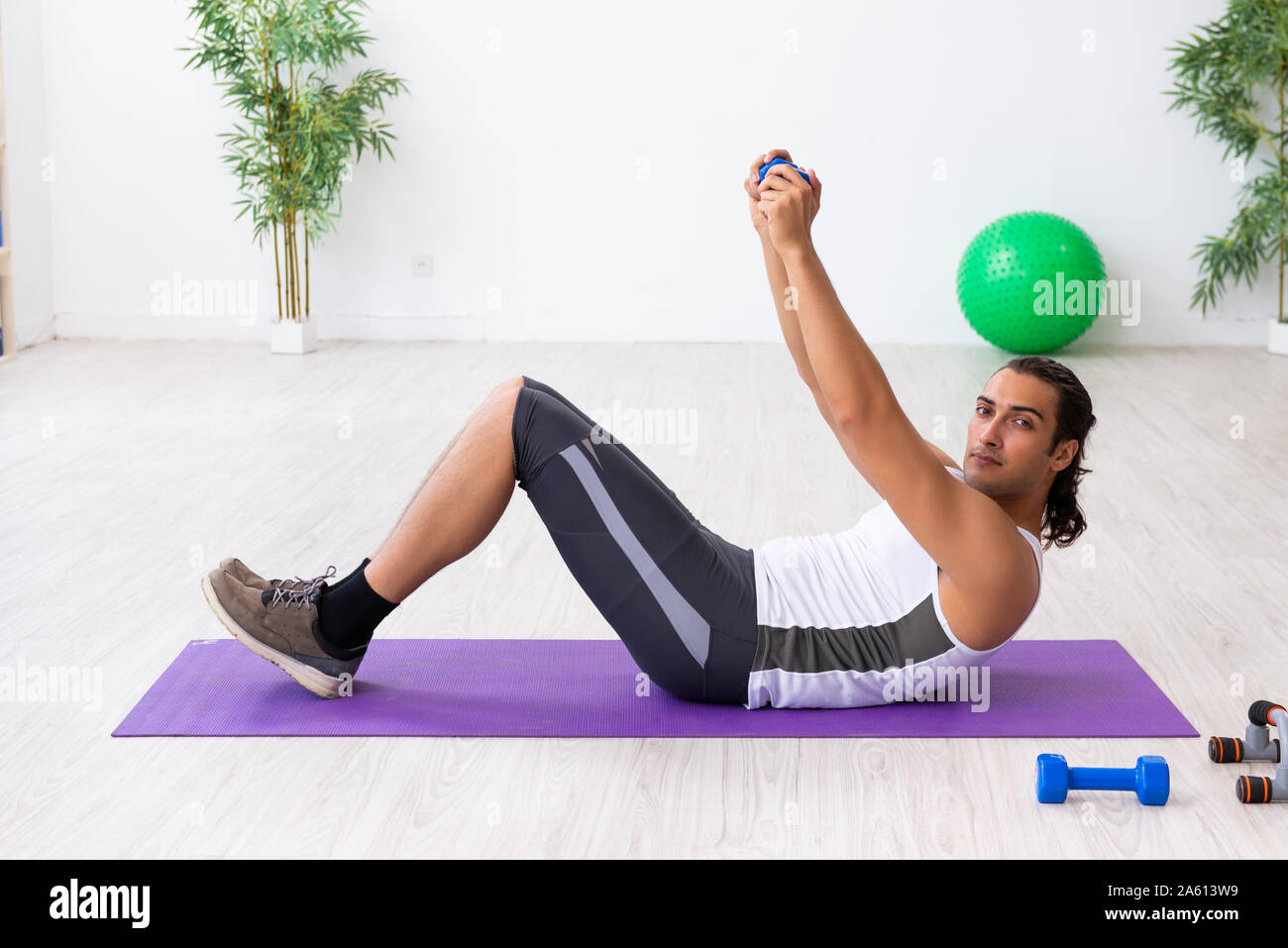 The young handsome man doing sport exercises indoors Stock Photo - Alamy