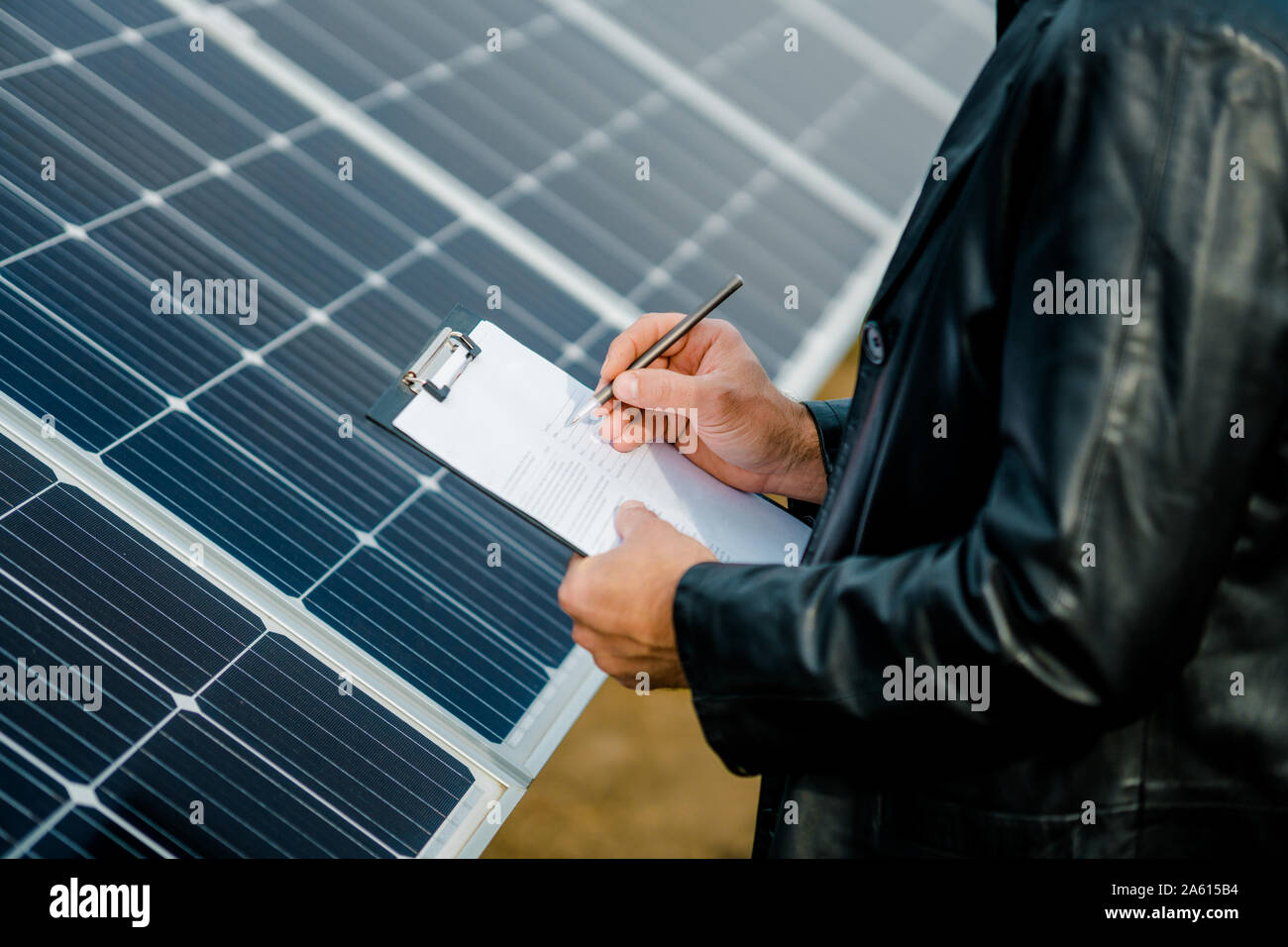 Man write notes on clipboard beside solar battery Stock Photo - Alamy
