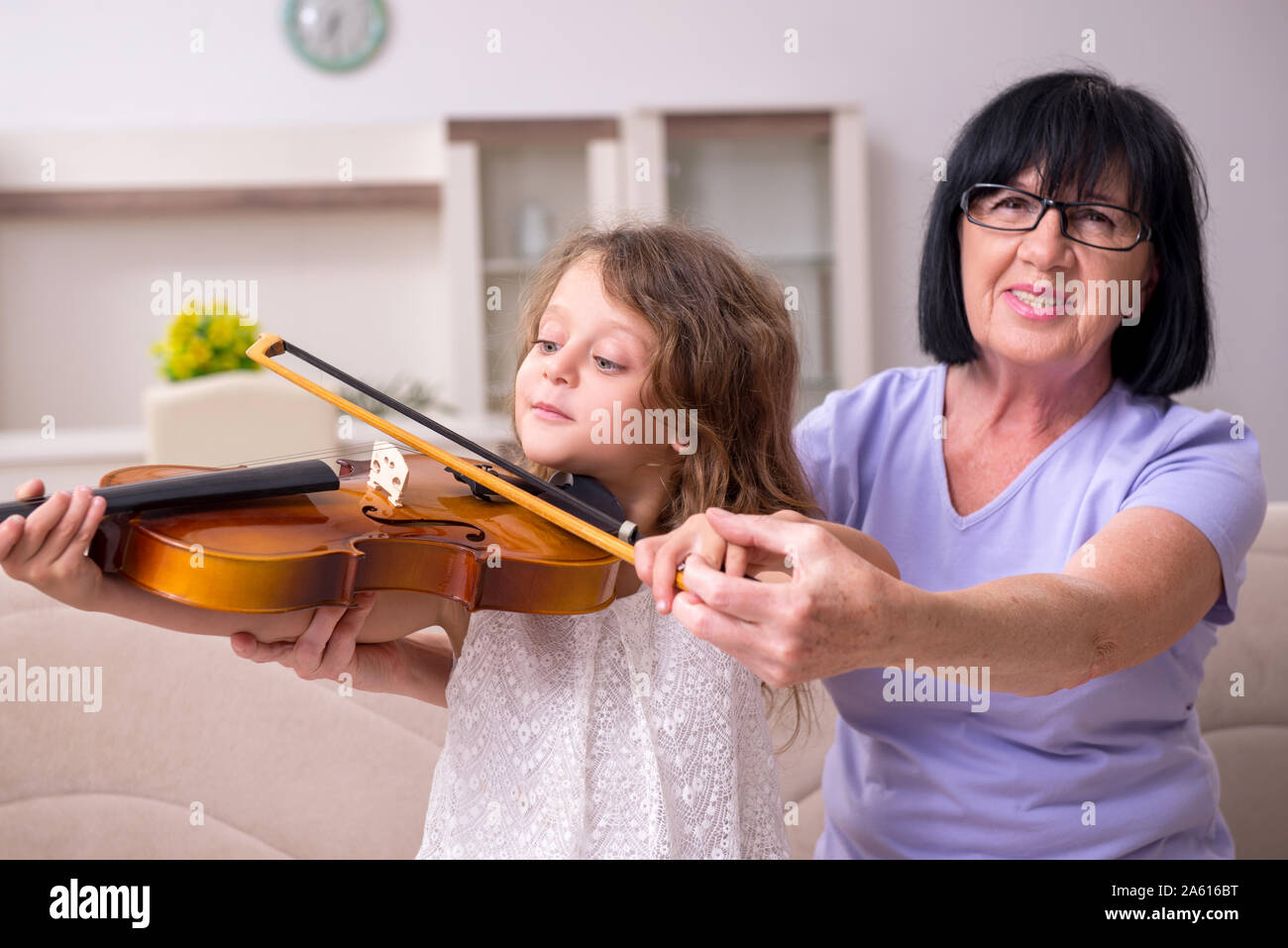 The old lady teaching little girl to play violin Stock Photo - Alamy