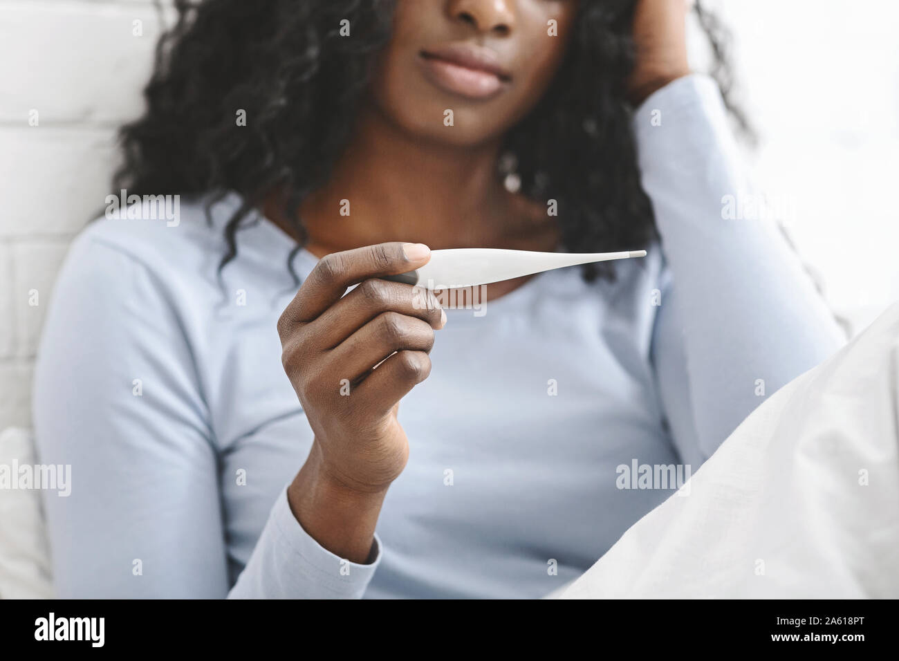 Sick woman with fever checking her temperature in bed Stock Photo - Alamy