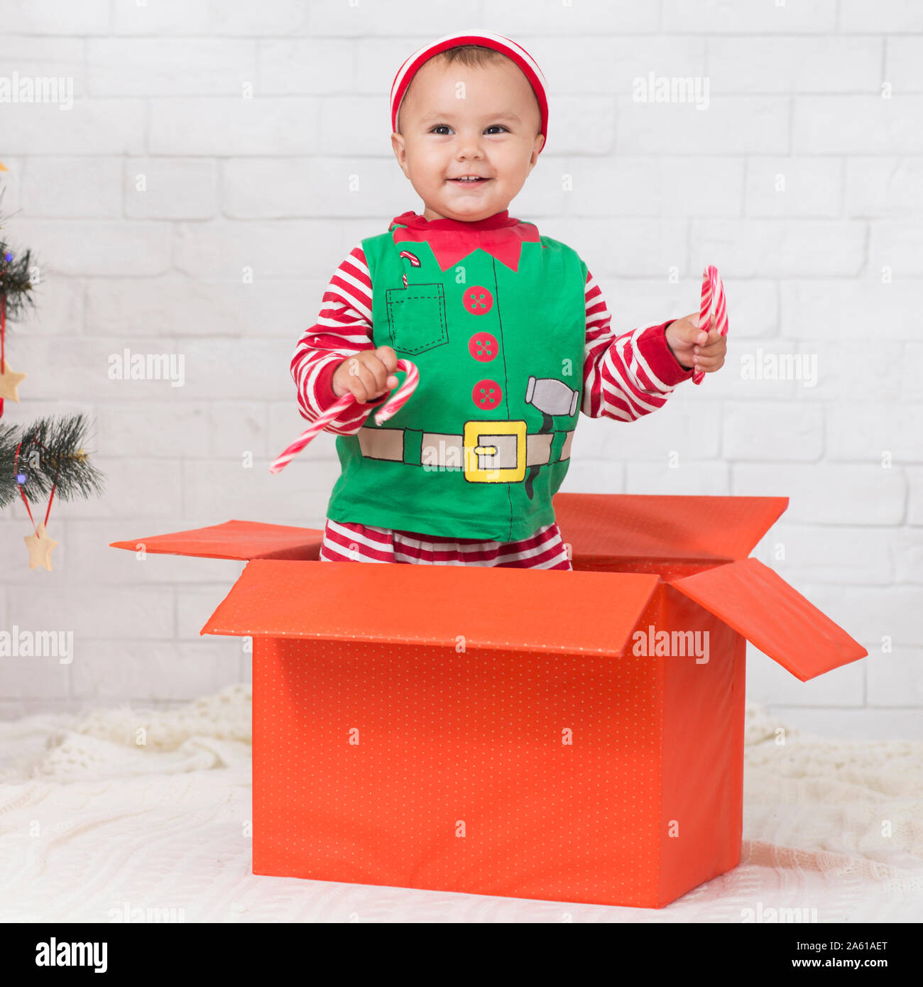 Adorable Santa helper with lollipops standing in big gift box Stock ...