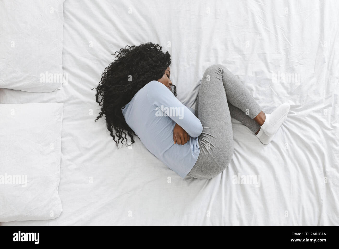 Top view of sick young woman lying in white bed Stock Photo - Alamy