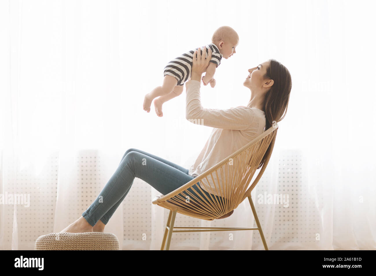 Mother sitting in wicker chair and playing with newborn child Stock ...