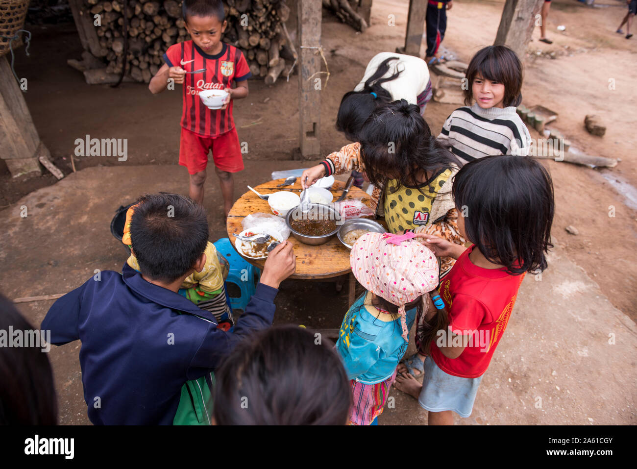Children in a Khmu village in Laos gather around a table, enjoying a ...