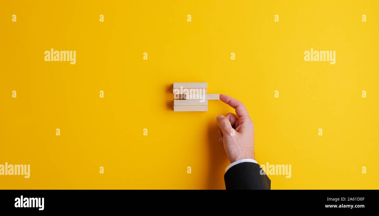 Hand of a businessman pushing wooden peg into a stack of them in a ...