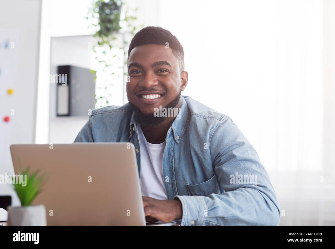 Portrait of smiling african employee at workplace in modern office ...
