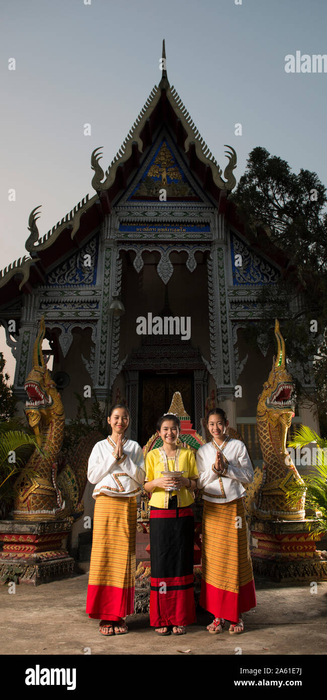 Young women in traditional attire pray at a village temple in Lampang ...