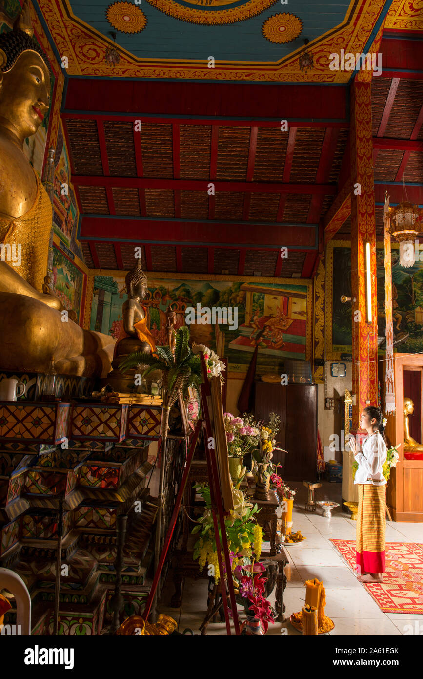 Young women in traditional attire pray at a village temple in Lampang ...