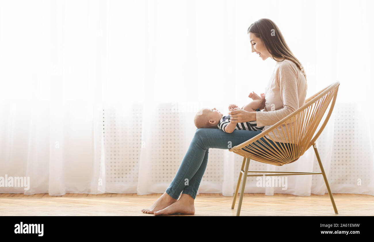 Mother sitting in wicker chair holding newborn baby on lap Stock Photo ...