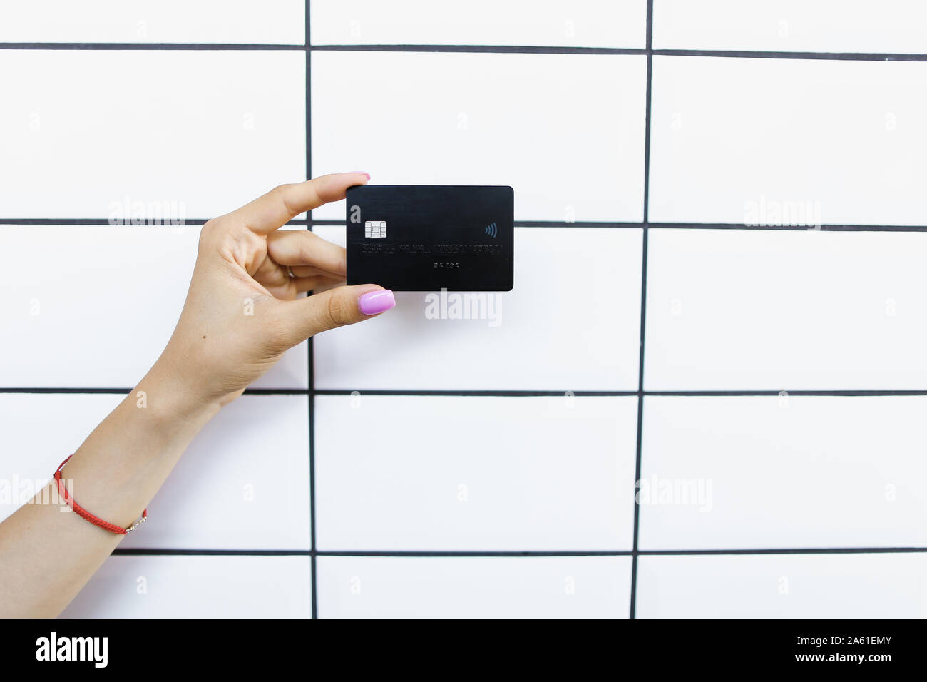 Female hands holding credit card in white tile wall background Stock ...