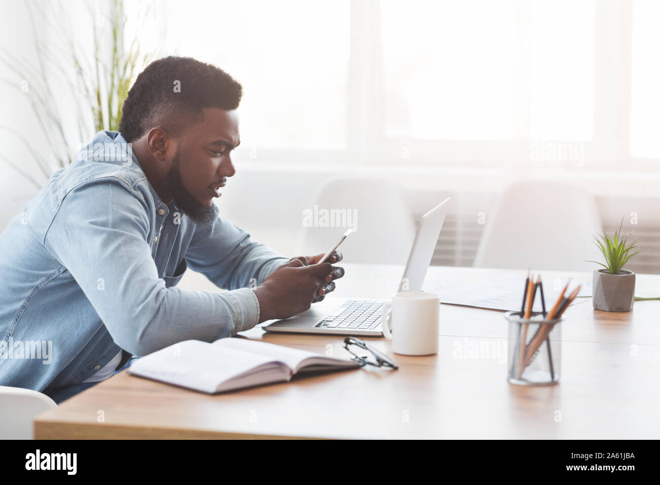 Black office worker using smartphone at workplace Stock Photo - Alamy