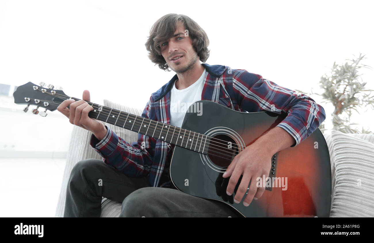 guy sings a song and plays guitar sitting on the couch Stock Photo - Alamy