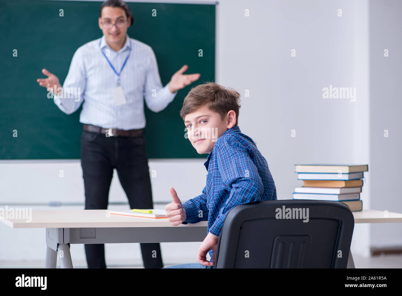 The young male teacher and boy in the classroom Stock Photo - Alamy