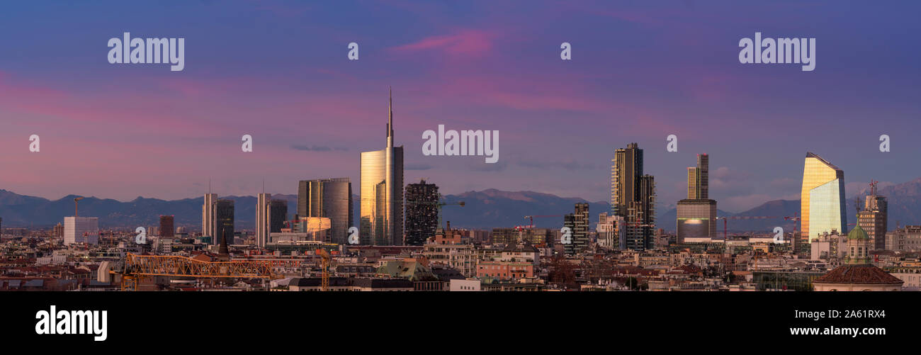 Aerial view of Milan skyline at sunset with alps mountains in the ...
