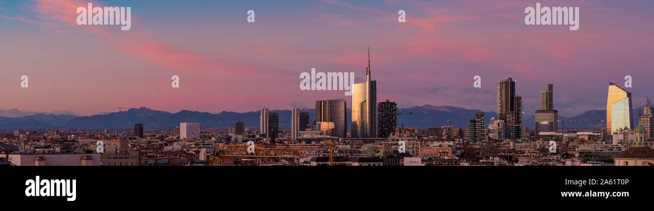Aerial view of Milan skyline at sunset with alps mountains in the ...