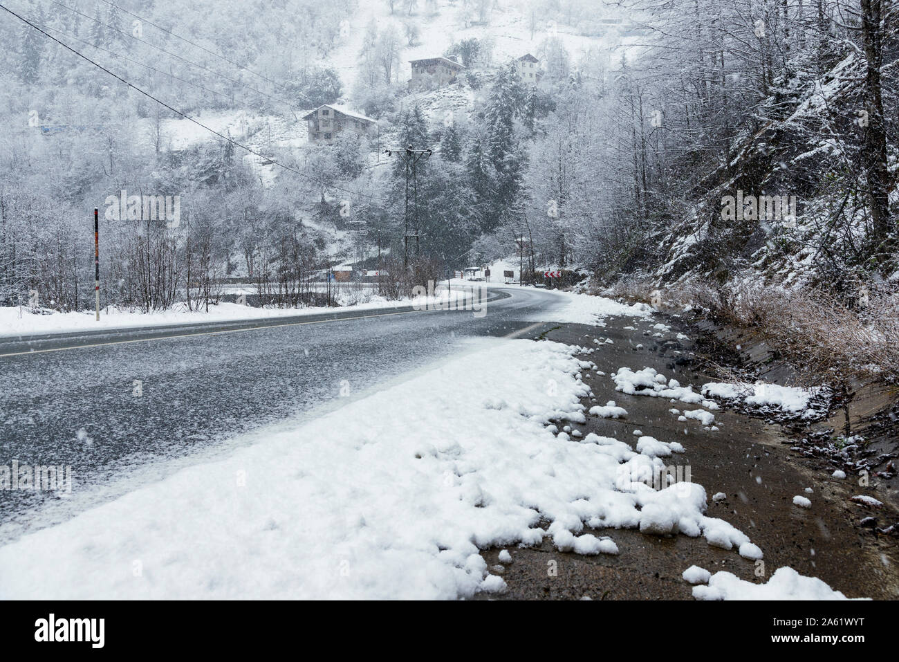 Snowy bending road scene in winter, with snowy trees, rocks and asphalt ...