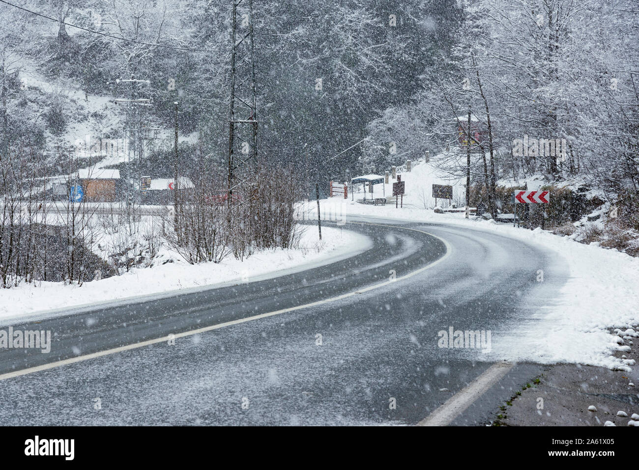 Snowy bending road scene in winter, with snowy trees, rocks and asphalt ...