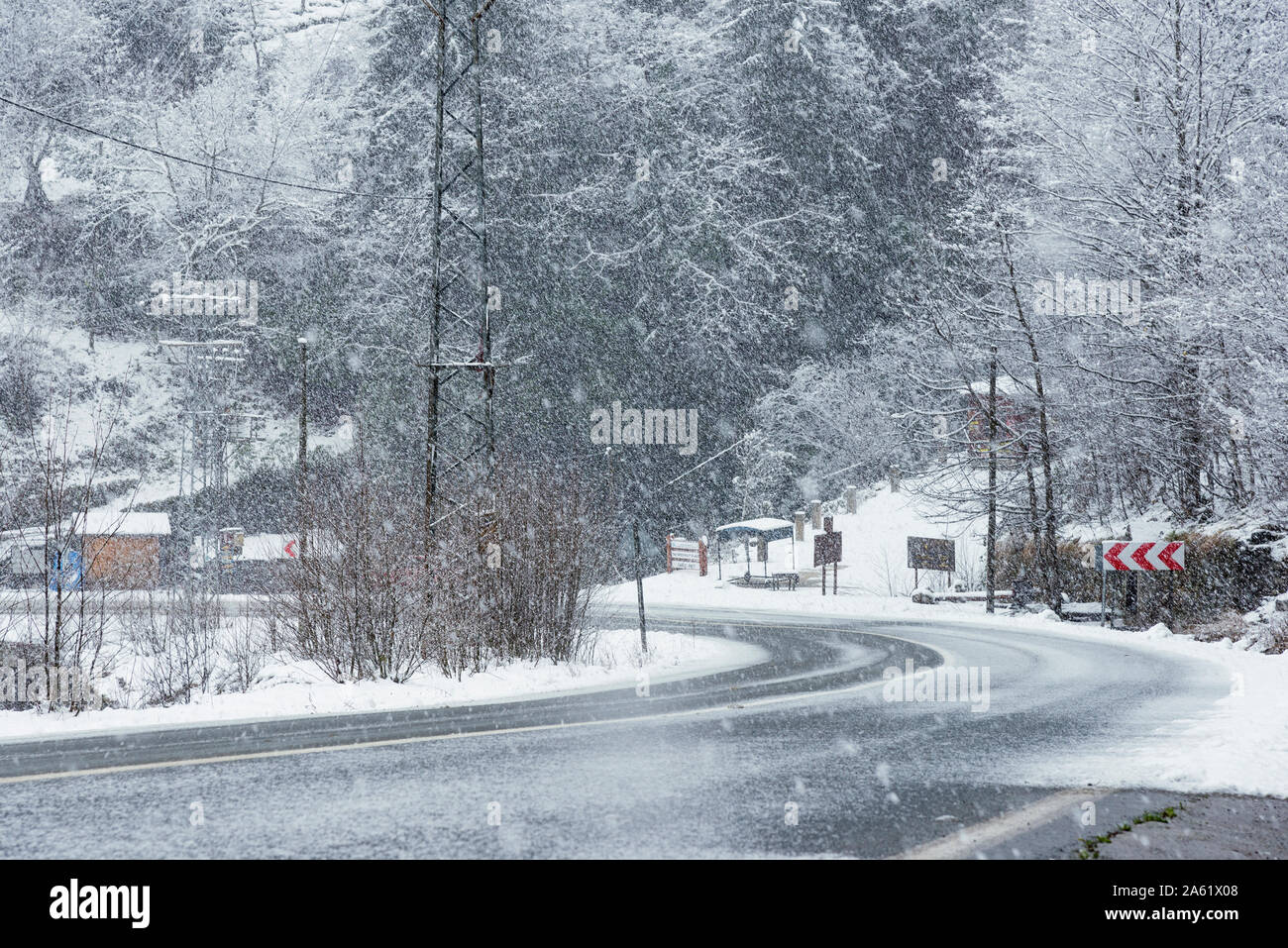 Snowy bending road scene in winter, with snowy trees, rocks and asphalt ...