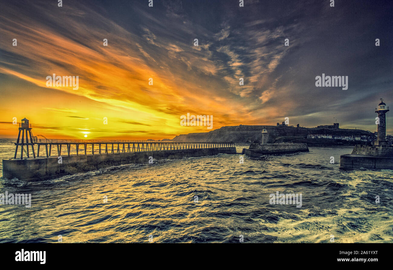 Whitby harbour at sunrise in Spring showing the lighthouse and jetty ...