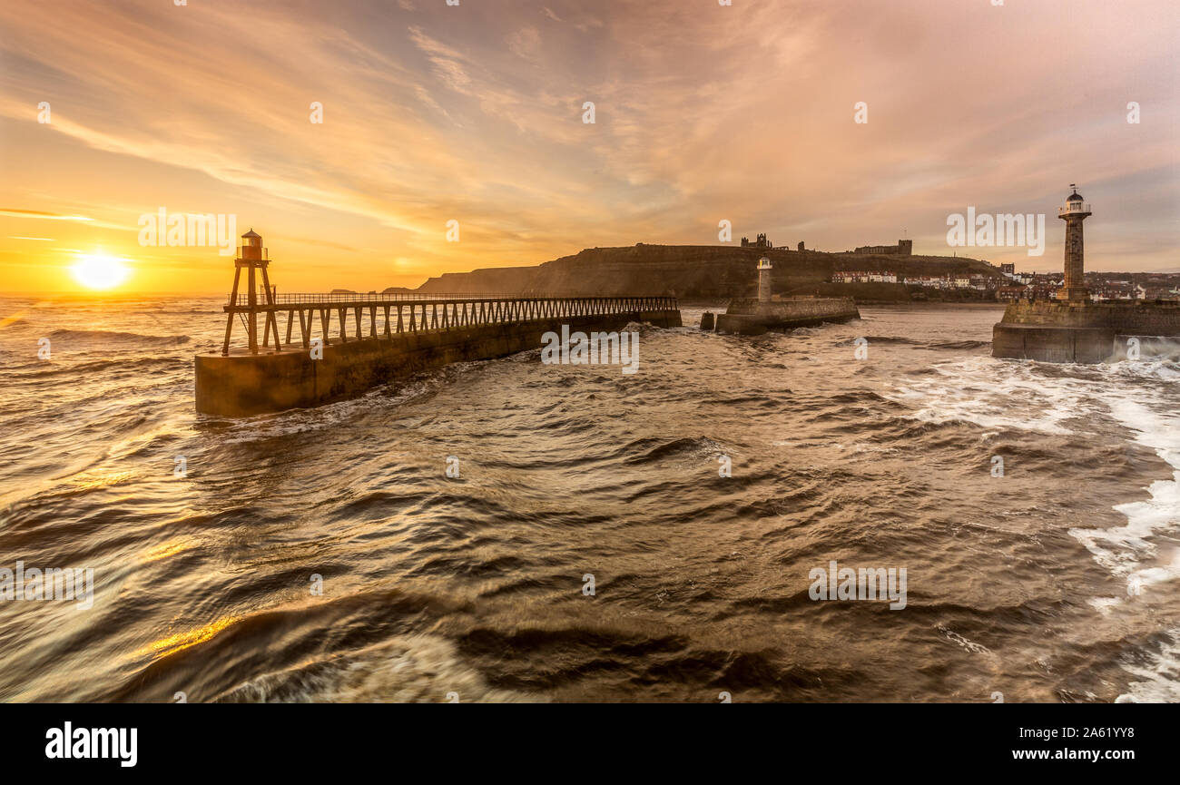 Whitby harbour at sunrise showing the jetty and lighthouse Stock Photo ...