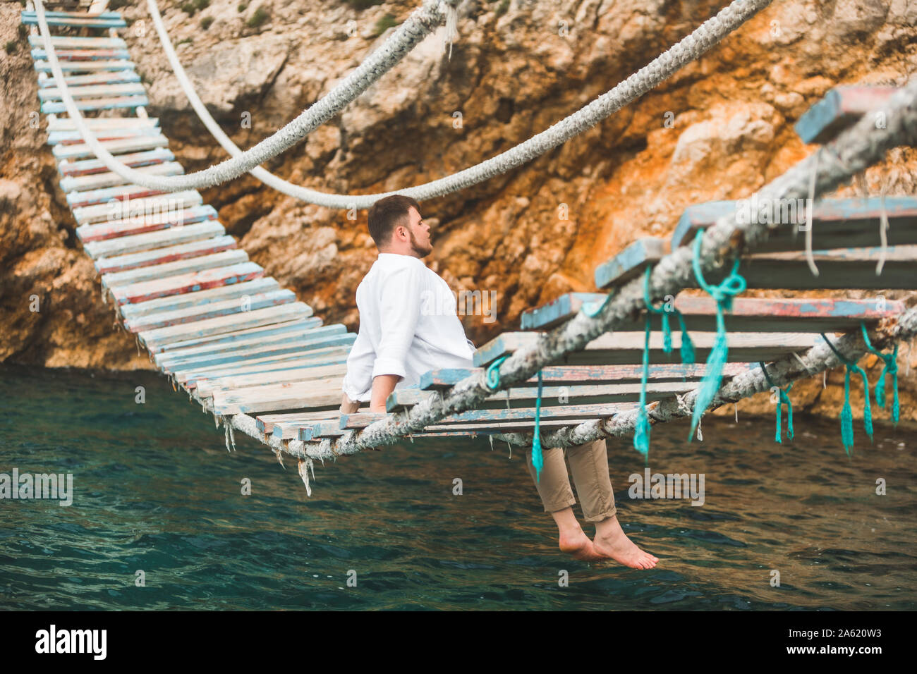 man sitting at suspension bridge enjoying sea view and nature calmness ...