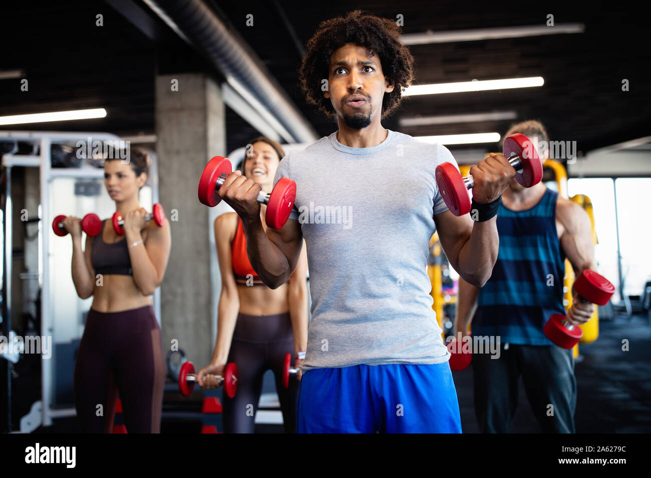 Healthy young people doing exercises at fitness studio Stock Photo - Alamy