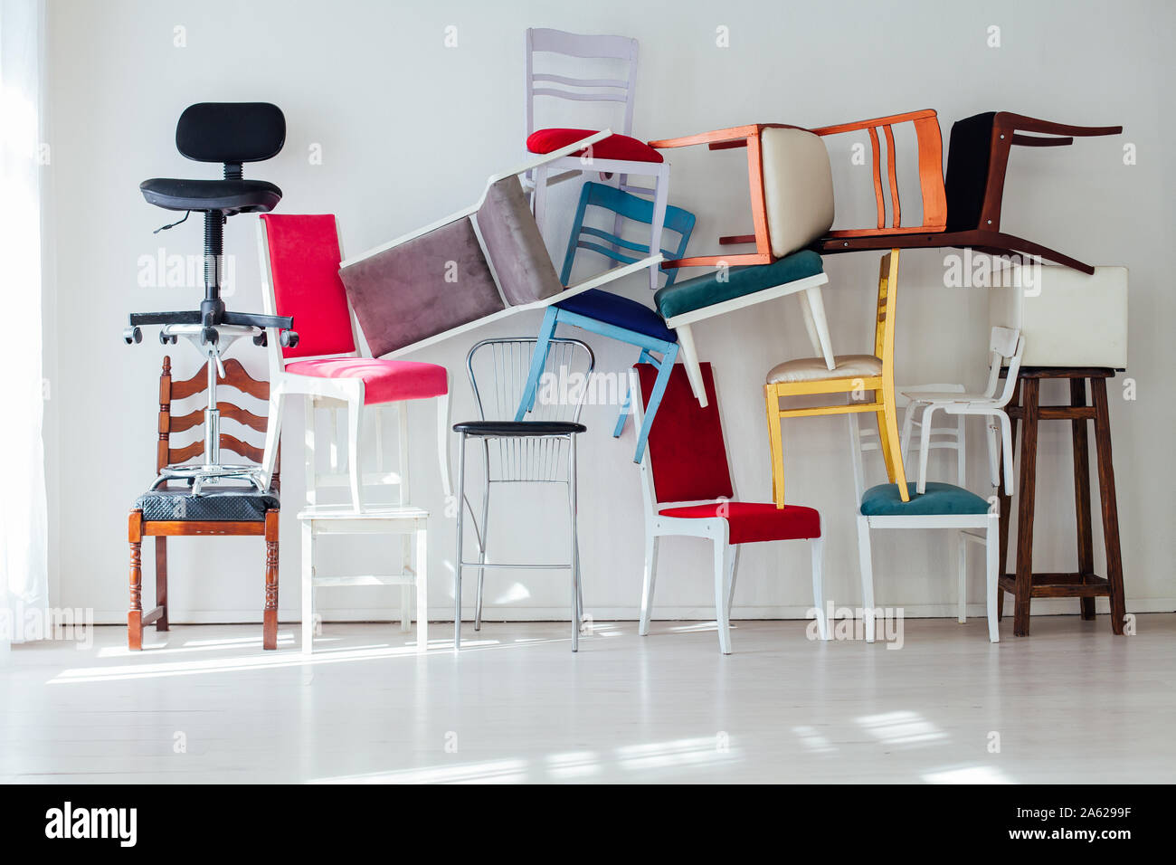 many multicolored chairs in the mess of the white room Stock Photo - Alamy