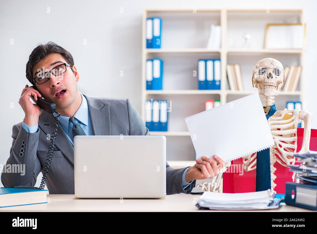The businessman working with skeleton in office Stock Photo - Alamy