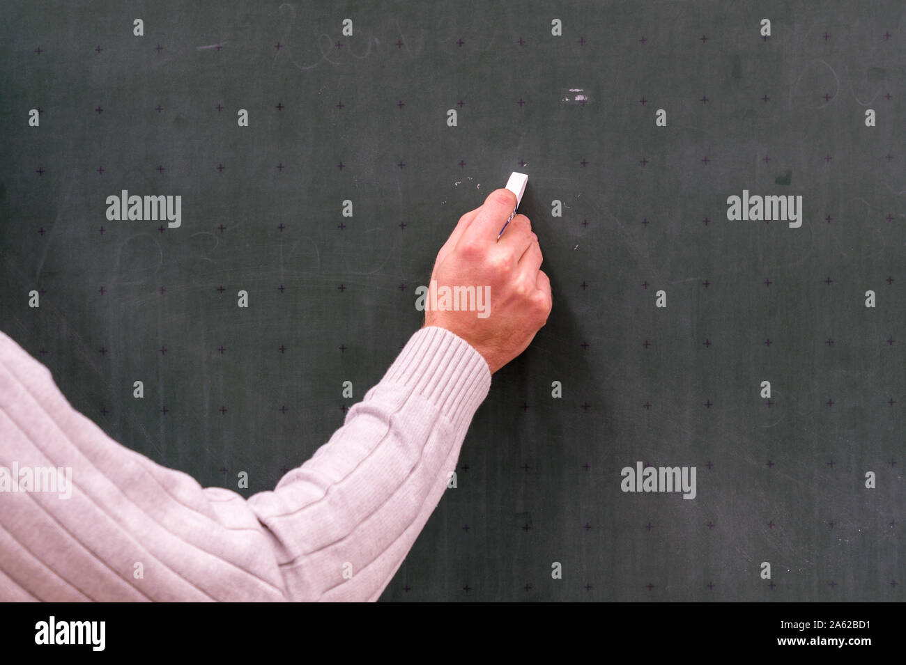 Teacher stands with chalk on the blackboard Stock Photo - Alamy