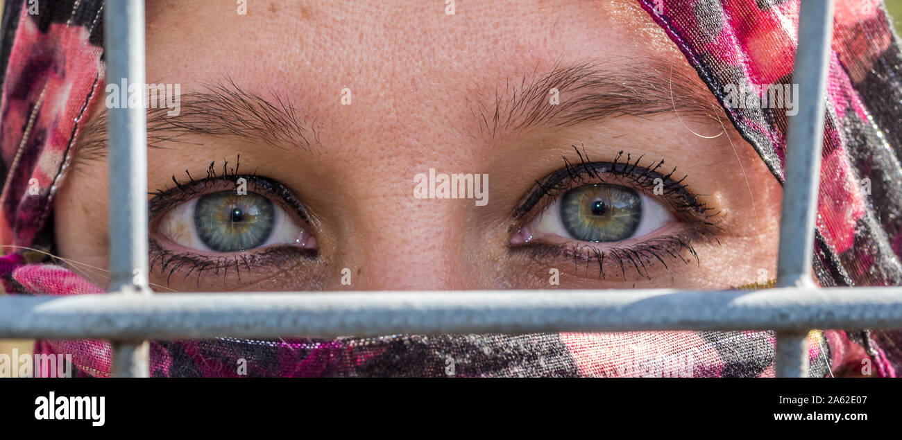 Muslim woman looks through the border fence Stock Photo - Alamy