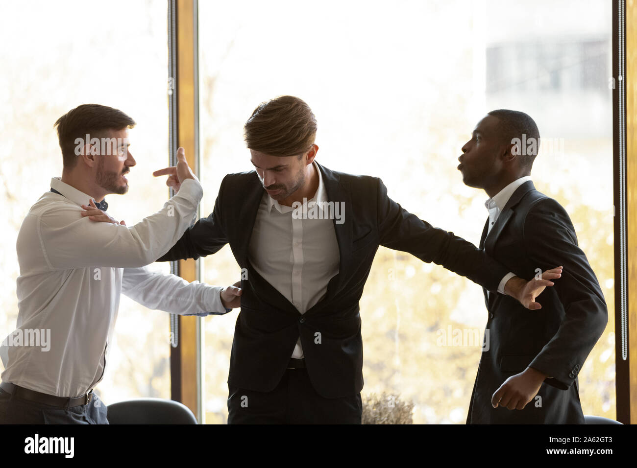 Male colleague set apart angry diverse businessmen fighting in office ...