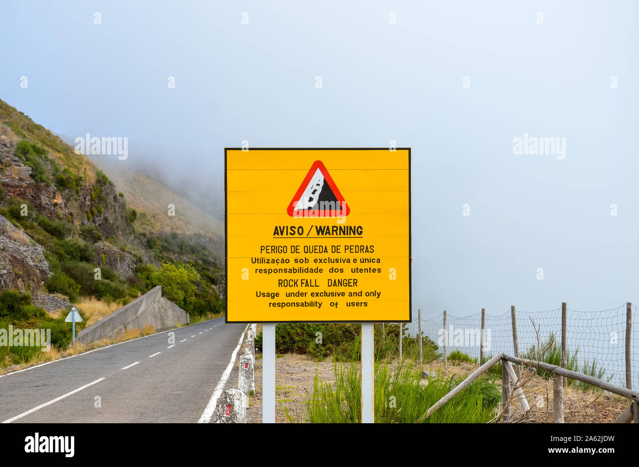 Yellow information sign warning of rockfall danger in Portuguese and ...