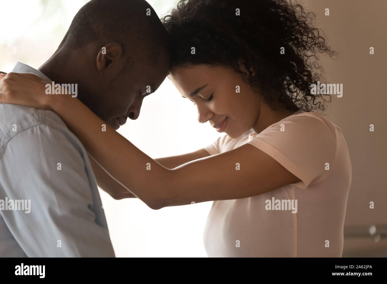 Side view happy african american woman cuddling beloved husband neck ...