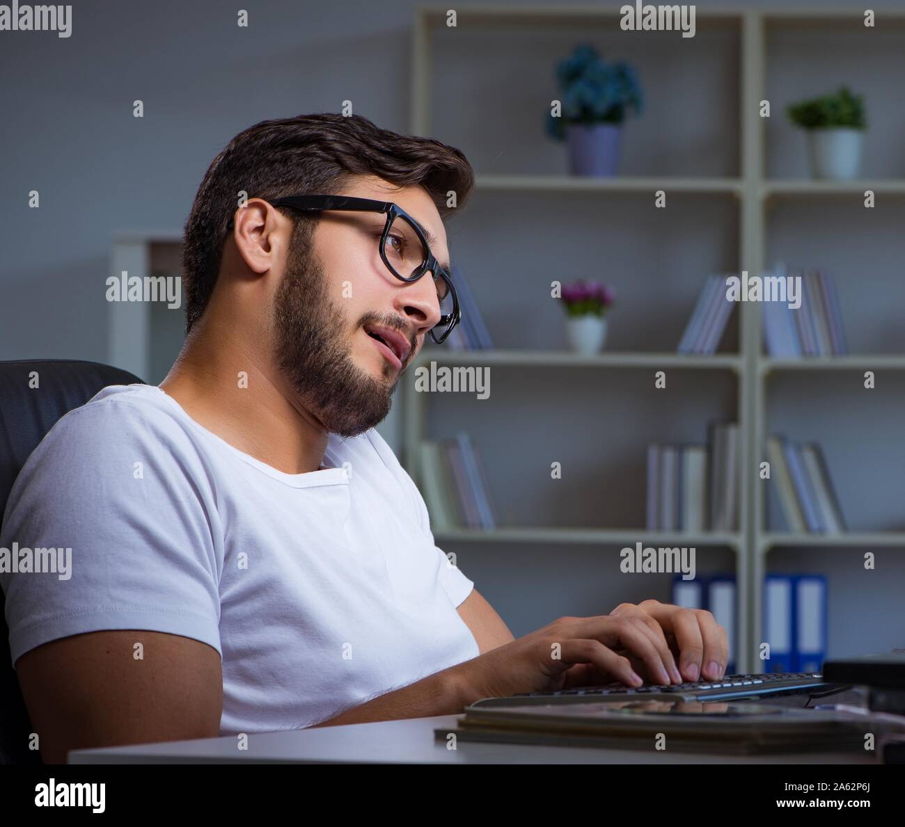 The young man staying late in office to do overtime work Stock Photo ...