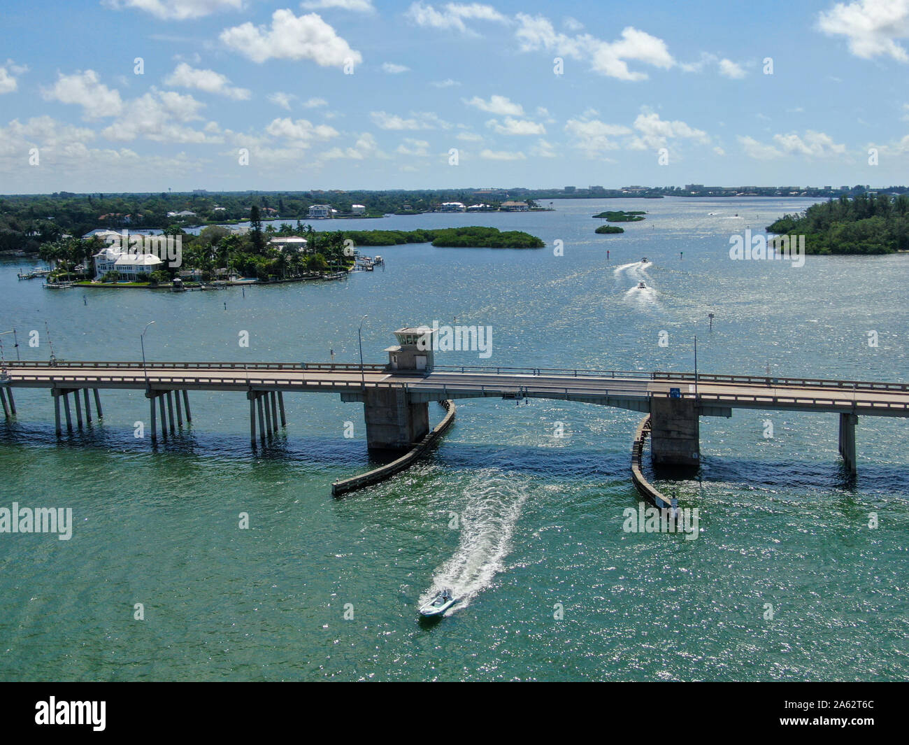Aerial view of open street bridge crossing ocean with small boat and ...