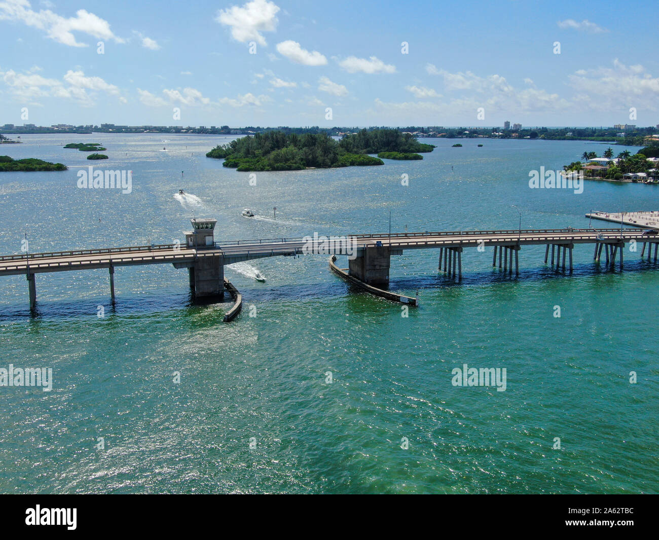 Aerial view of open street bridge crossing ocean with small boat and ...