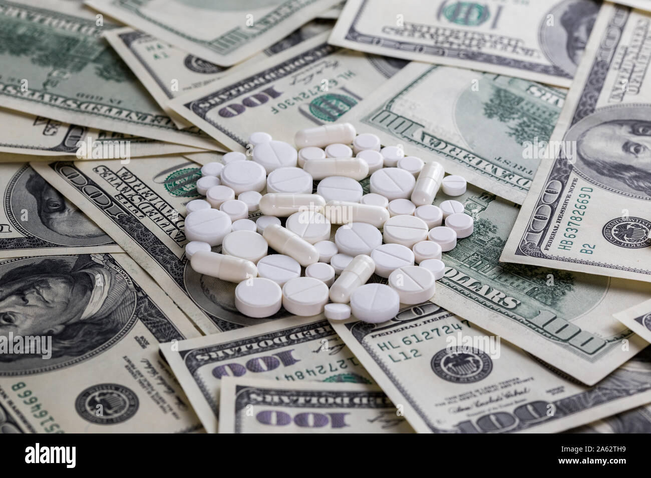 handful of white pills on dollar bills close-up with selective focus ...
