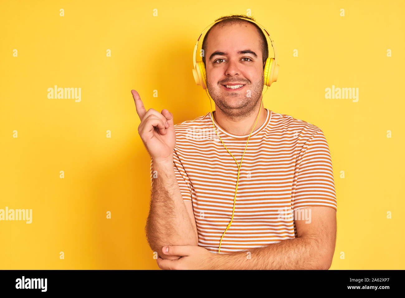 Young man listening to music using headphones standing over isolated ...