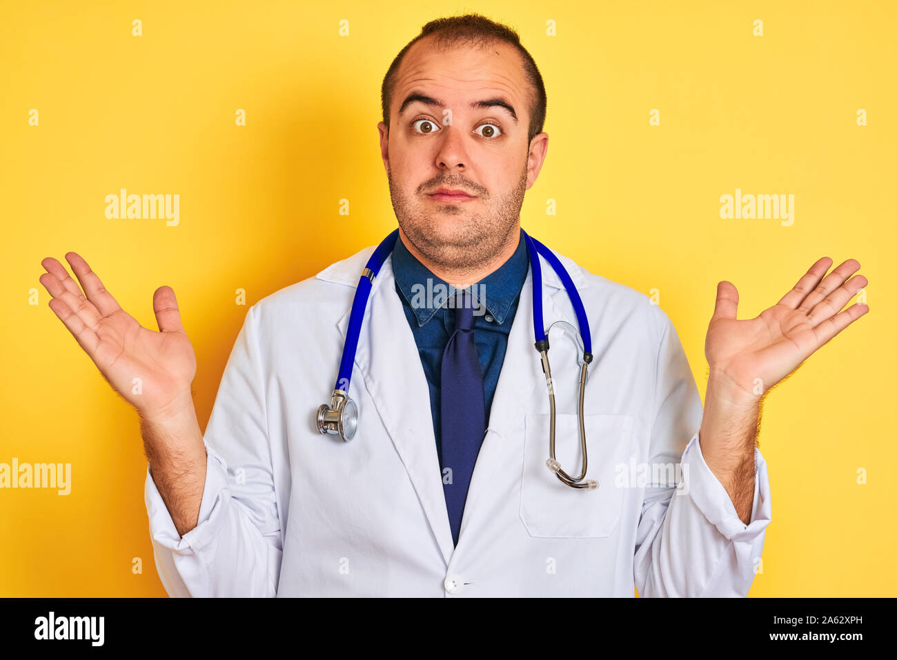 Young doctor man wearing coat and stethoscope standing over isolated ...