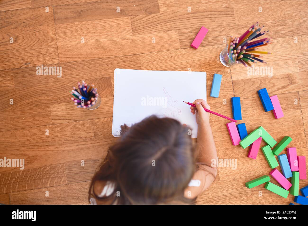 Adorable toddler lying down on the floor drawing using paper and ...