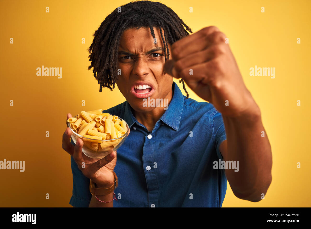 Afro american man with dreadlocks holding pasta macaroni over isolated ...