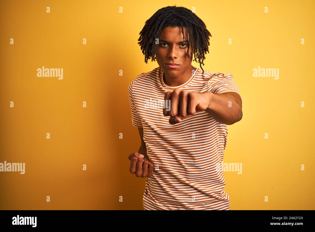 Afro man with dreadlocks wearing striped t-shirt standing over isolated ...