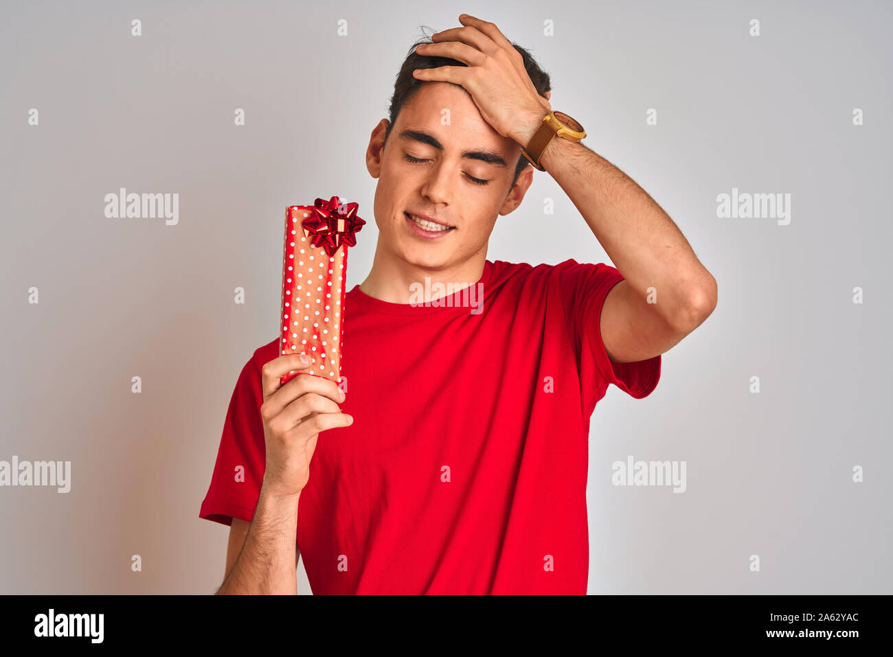 Teenager boy holding birthday gift over isolated background stressed ...